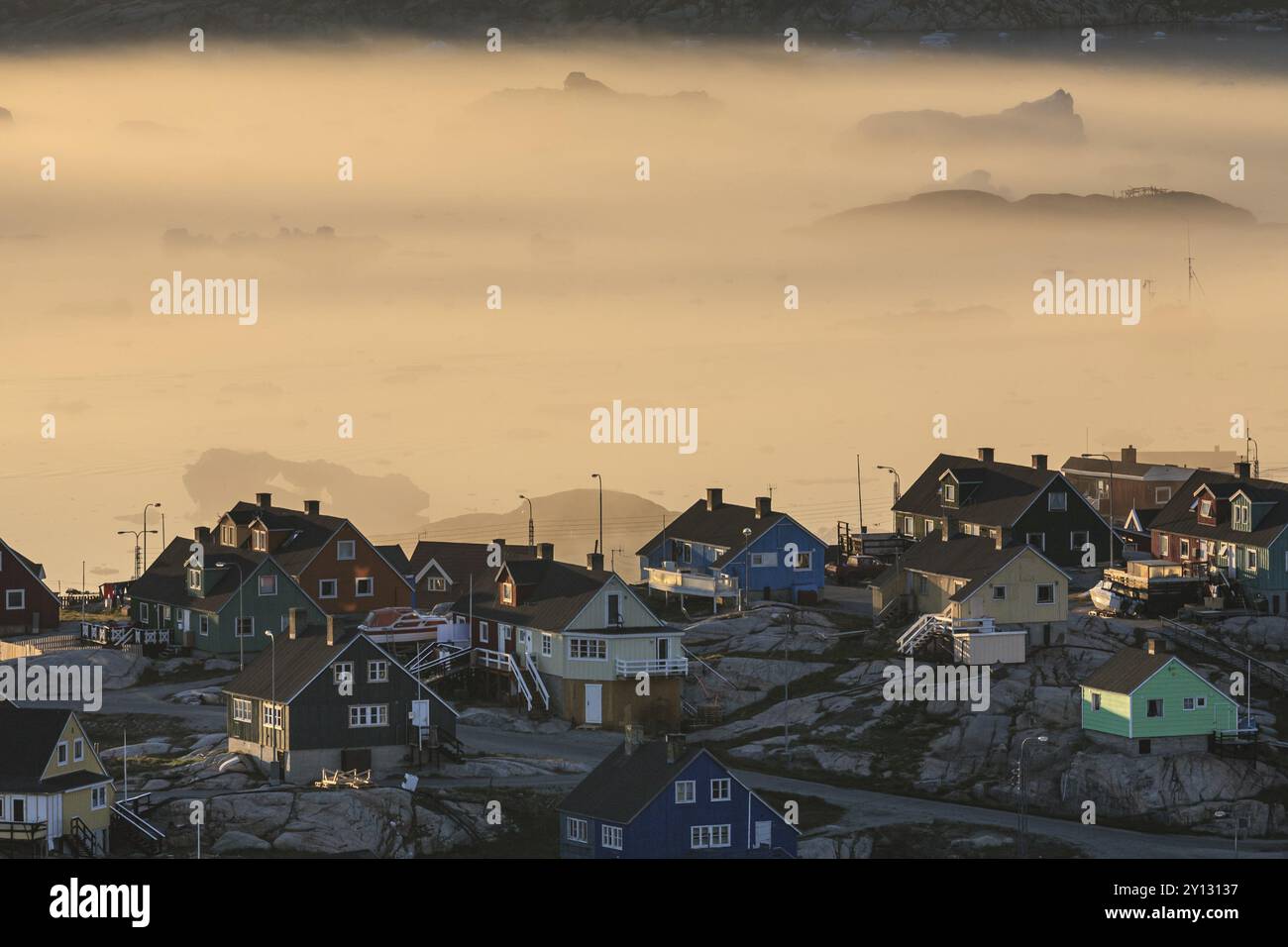 Inuit settlement in front of icebergs in the fog, midnight sun, summer ...