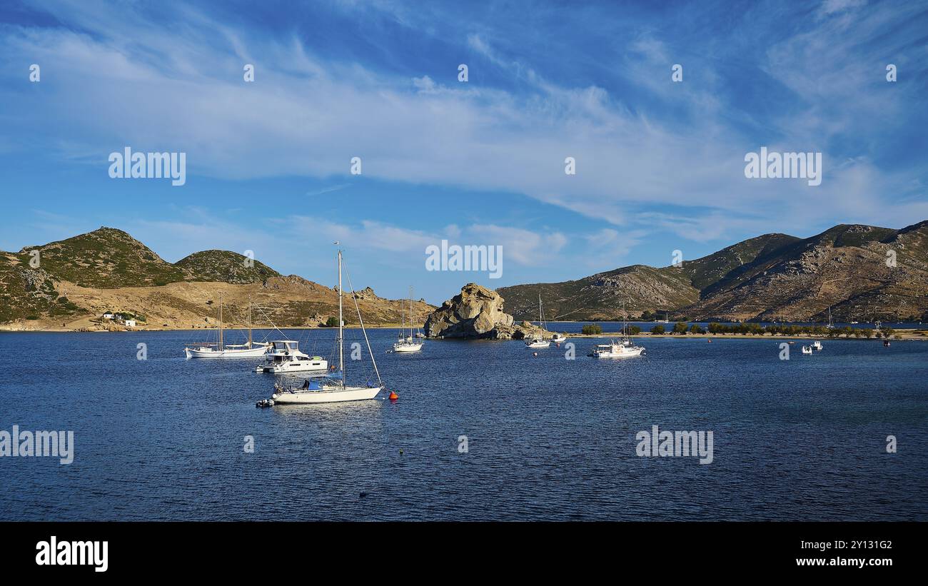 Boats on calm blue water, surrounded by mountains and rocks under a ...