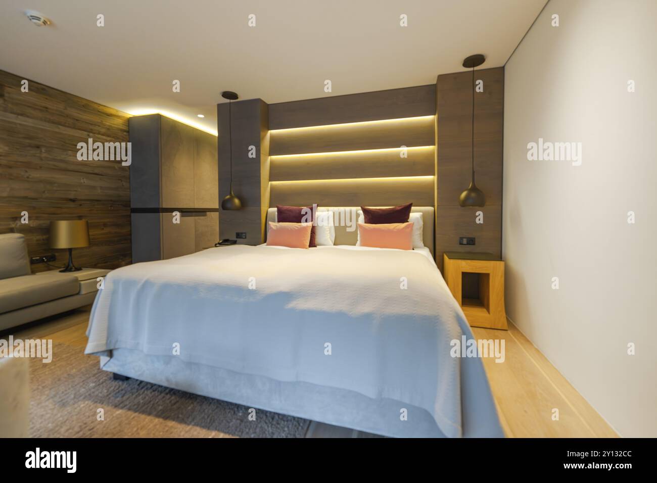 Modern bedroom with large bed, backlit wall and wood panelling ...