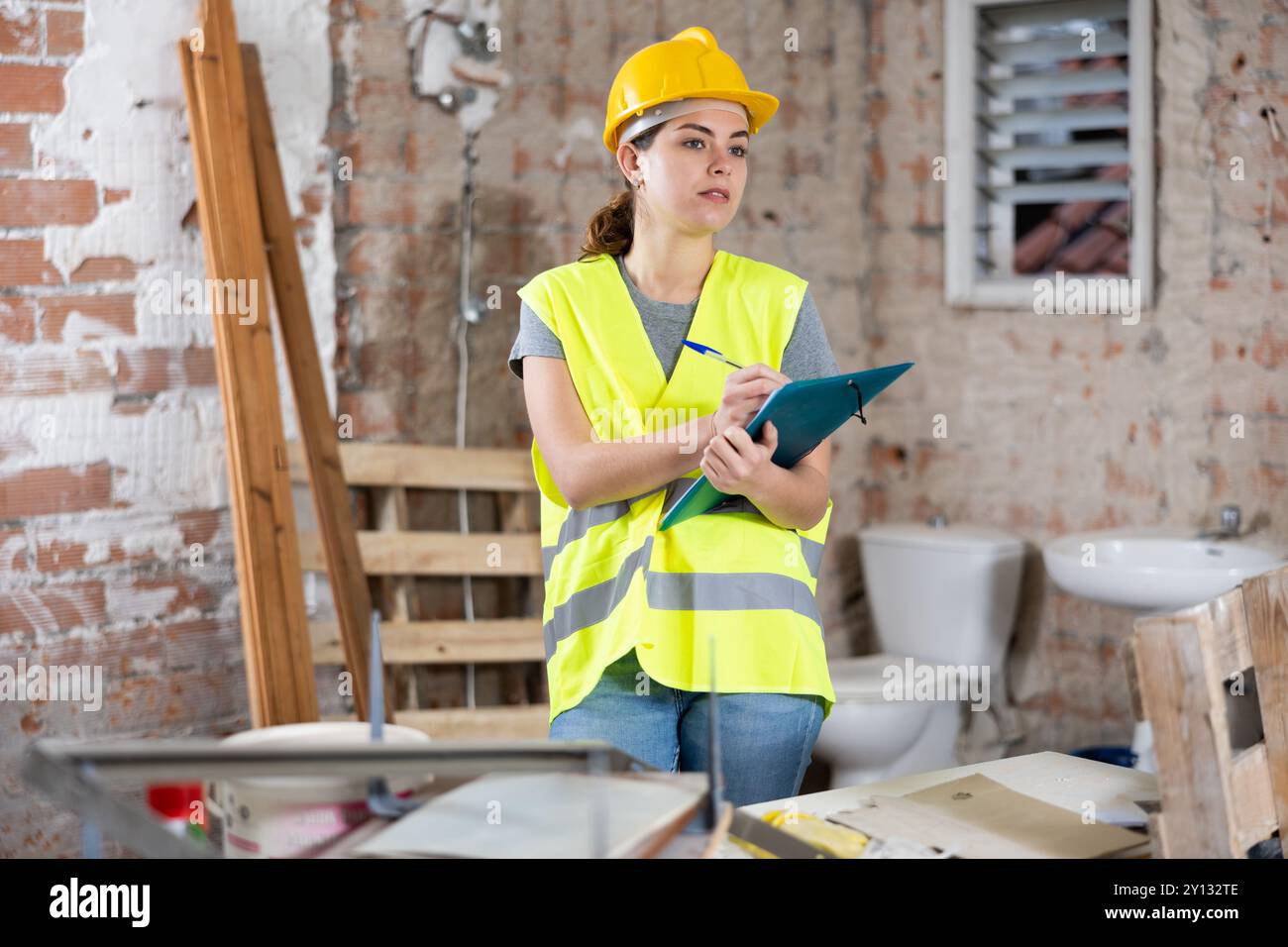 Female civil engineer making notes while controlling construction site ...