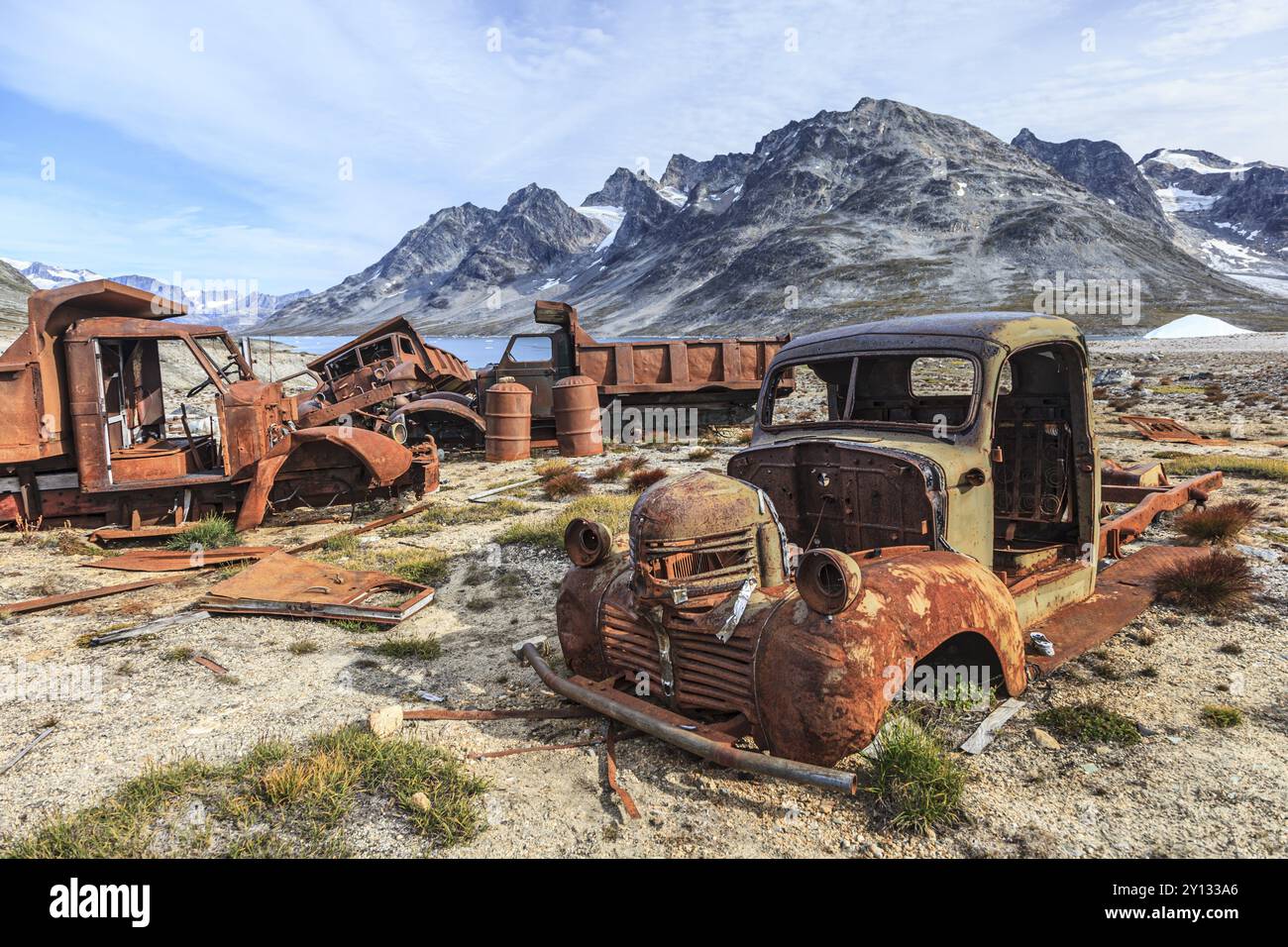 Rusty cars and oil drums in front of steep mountains, remains of a US ...