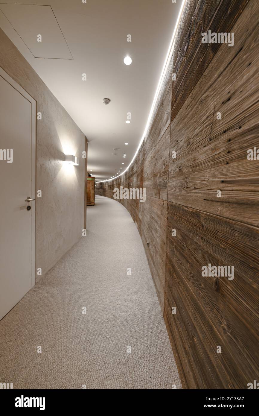 A long curved corridor with wooden panelling and modern lighting ...