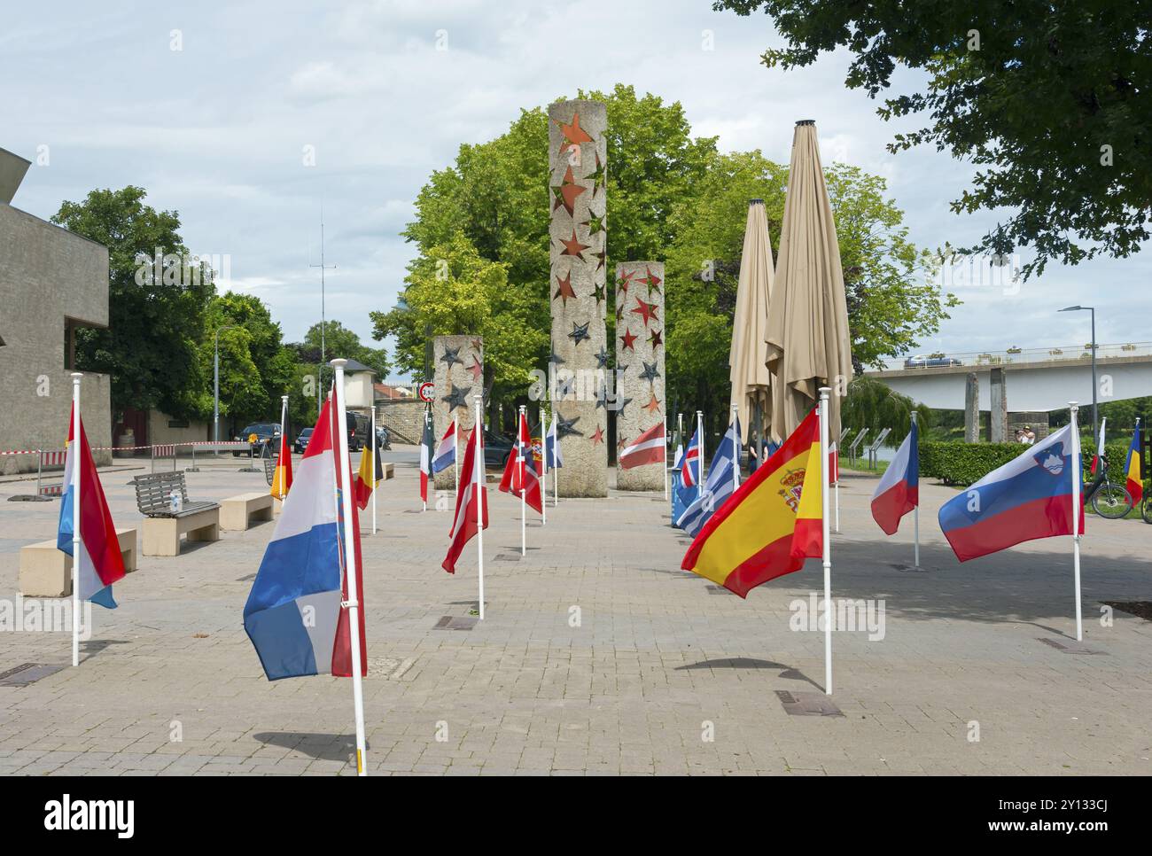 Flags of different countries in front of several pillars in an outdoor ...
