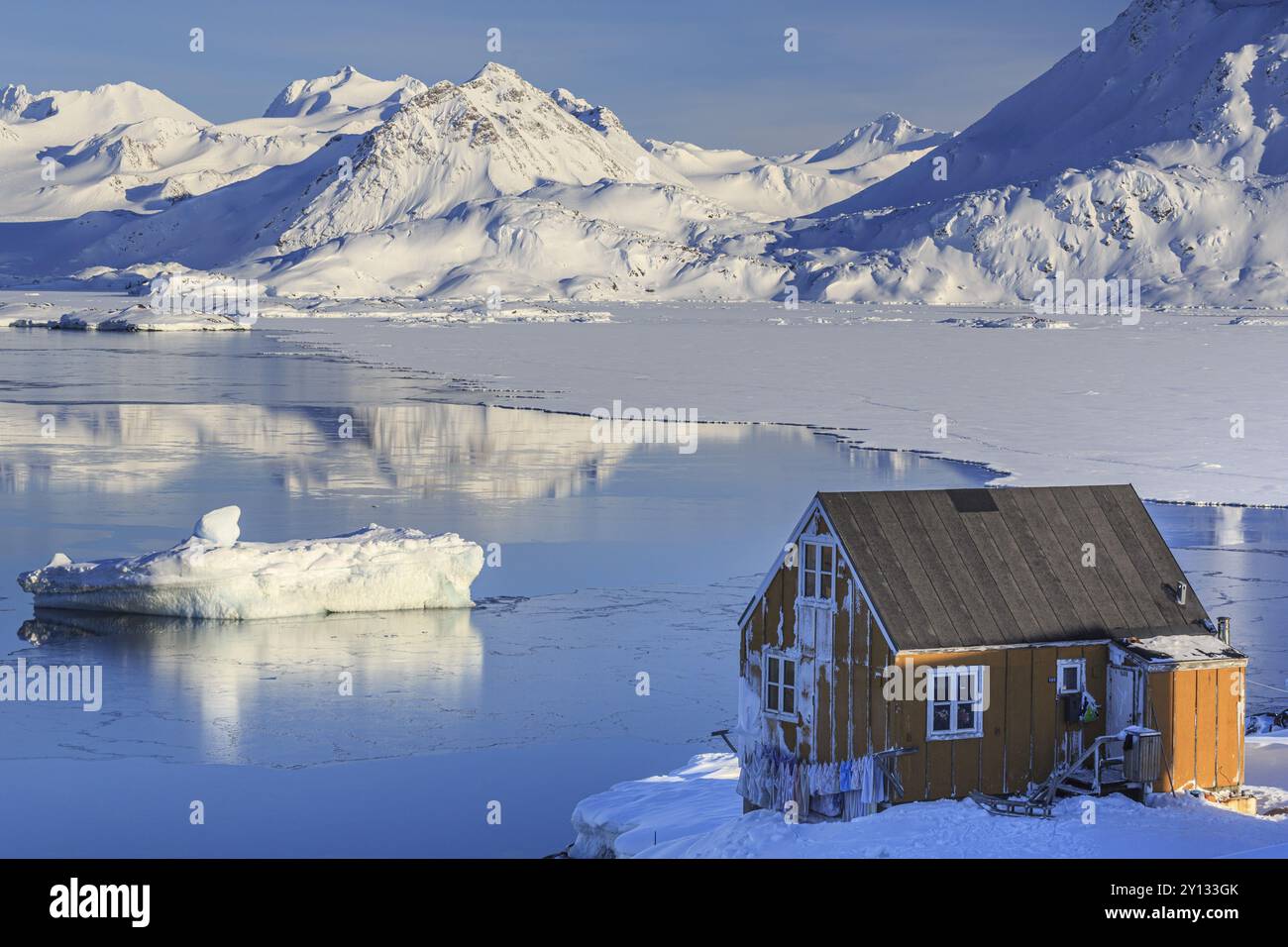 Typical Greenlandic house in front of icebergs, fjord and snowy ...