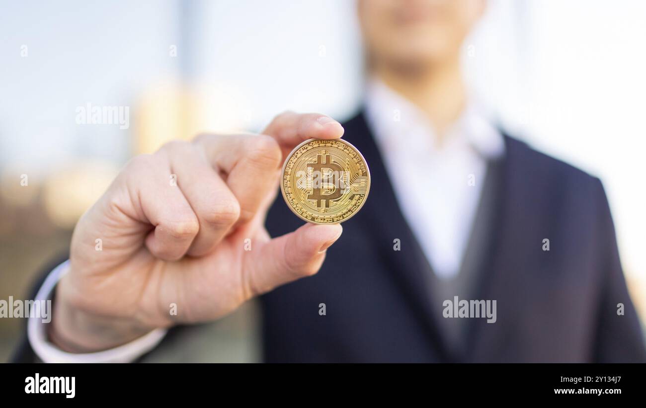 Bitcoin cryptocurrency coin in a young businessman hand. Disruptive ...