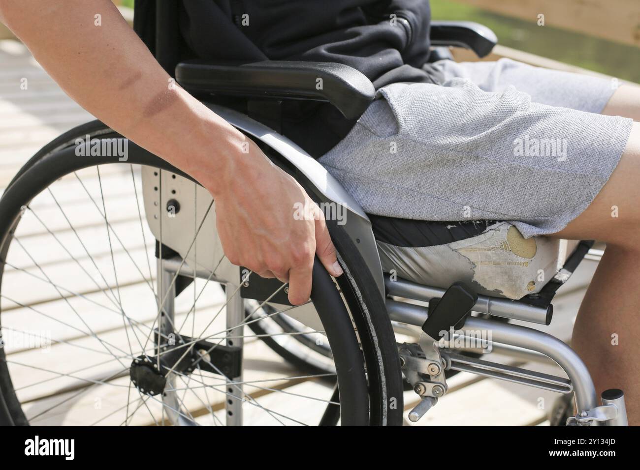 Disabled young athletic man on a wheelchair holding and turning wheels ...