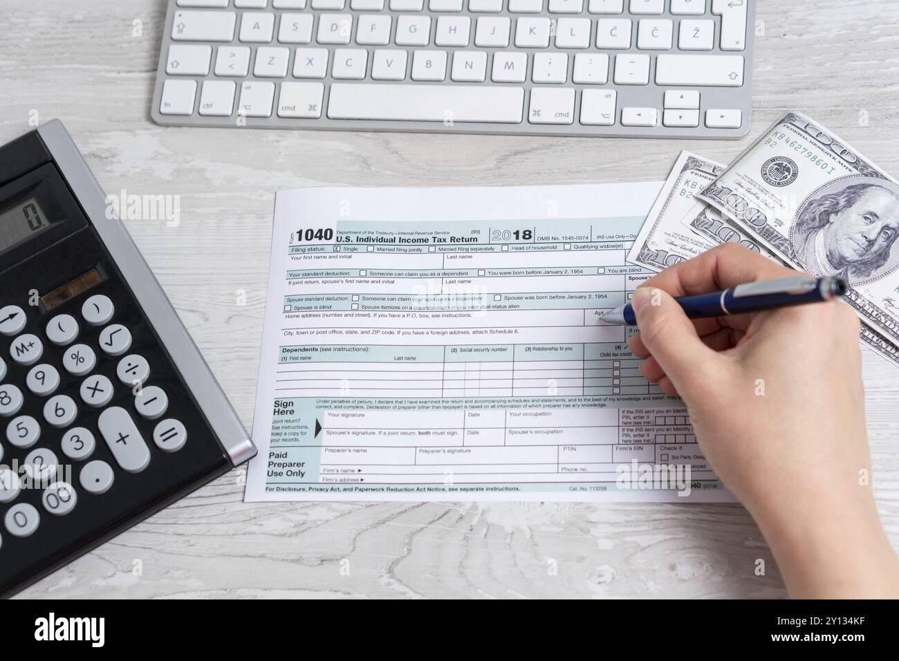 Point of view photo of woman calculating and filling US tax form next ...