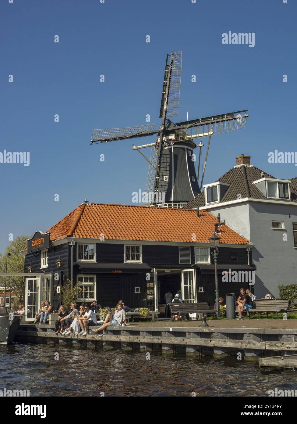 People enjoying the weather in front of a windmill with a neighbouring ...