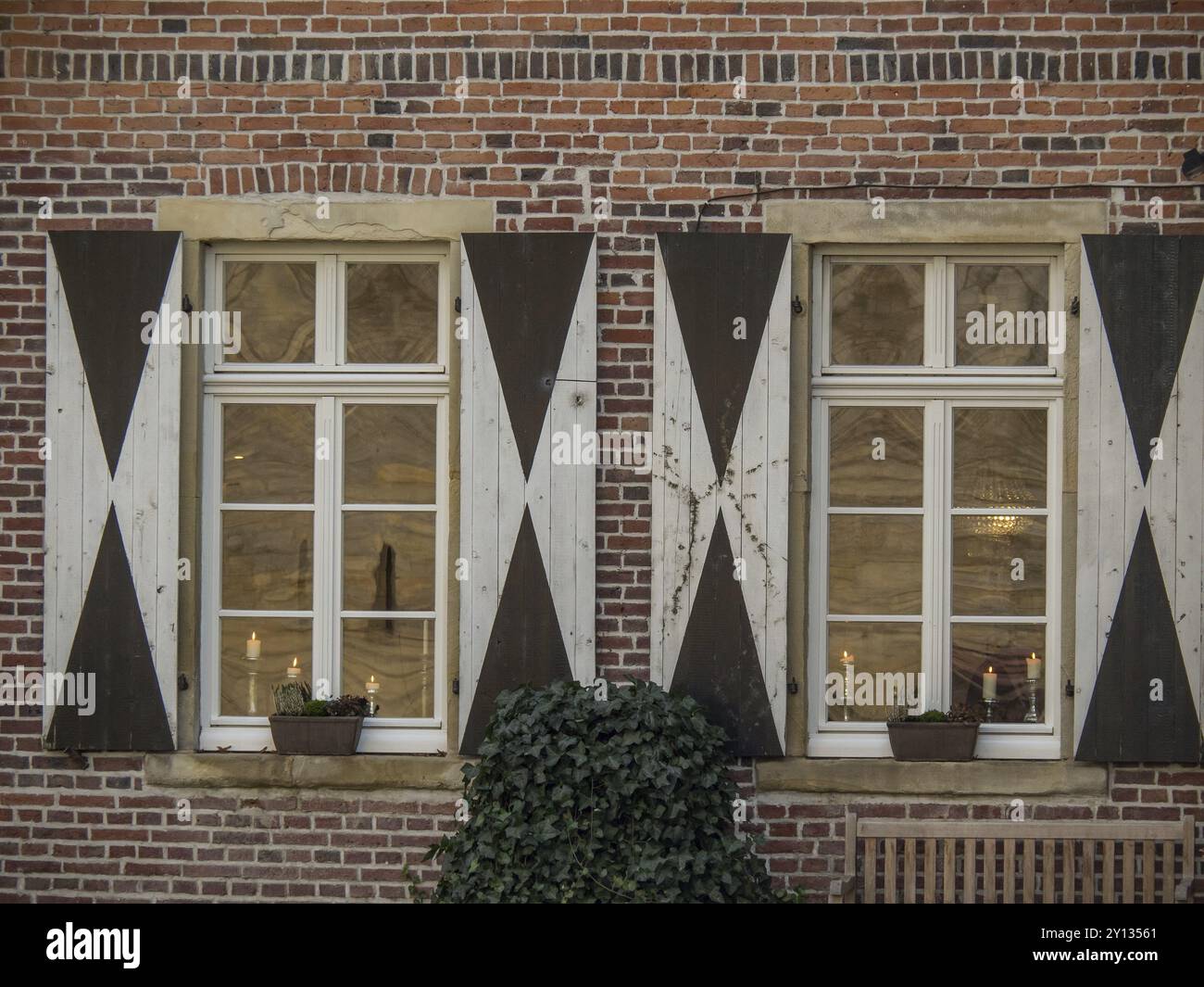 Two whitewashed windows with shutters on a brick wall, decorated with ...