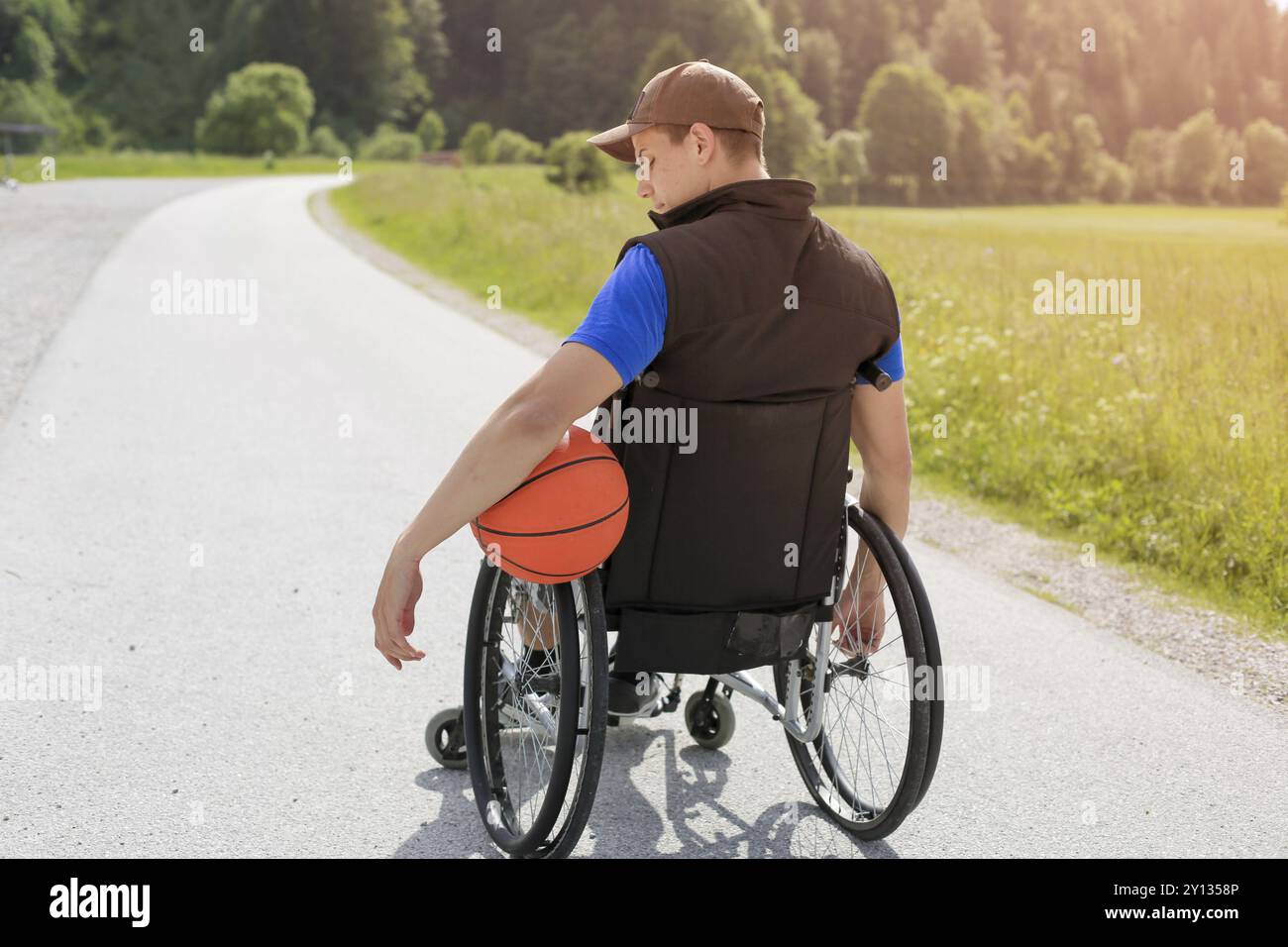 Disabled young basketball player on a wheelchair holding ball and ...