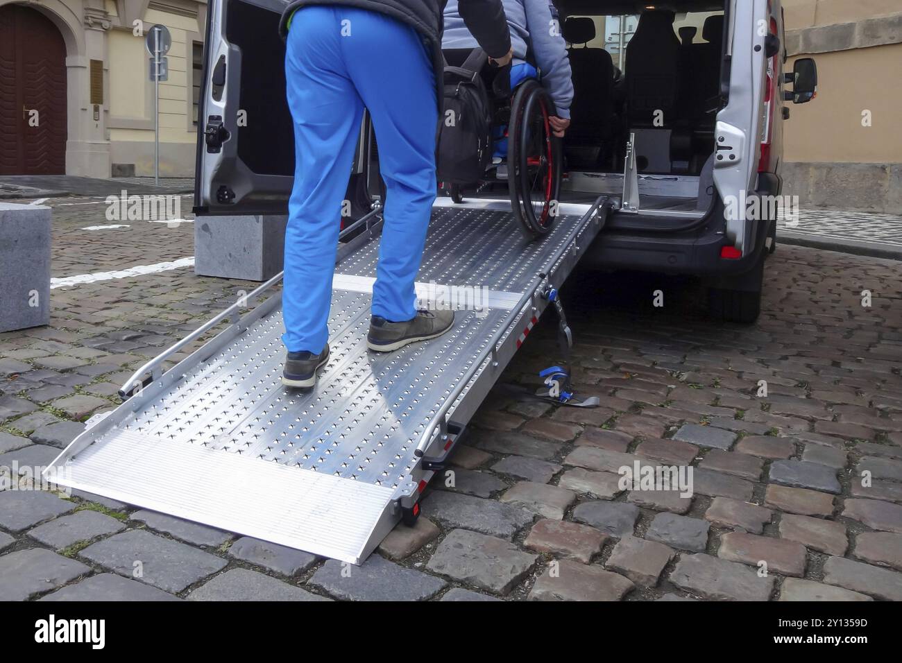 Assistant helping disabled person on wheelchair with transport using ...