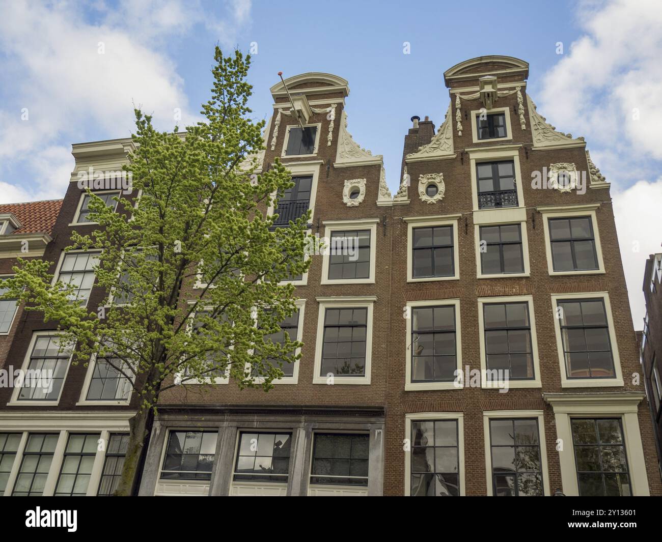 Historic buildings with striking facades and large windows, trees in ...