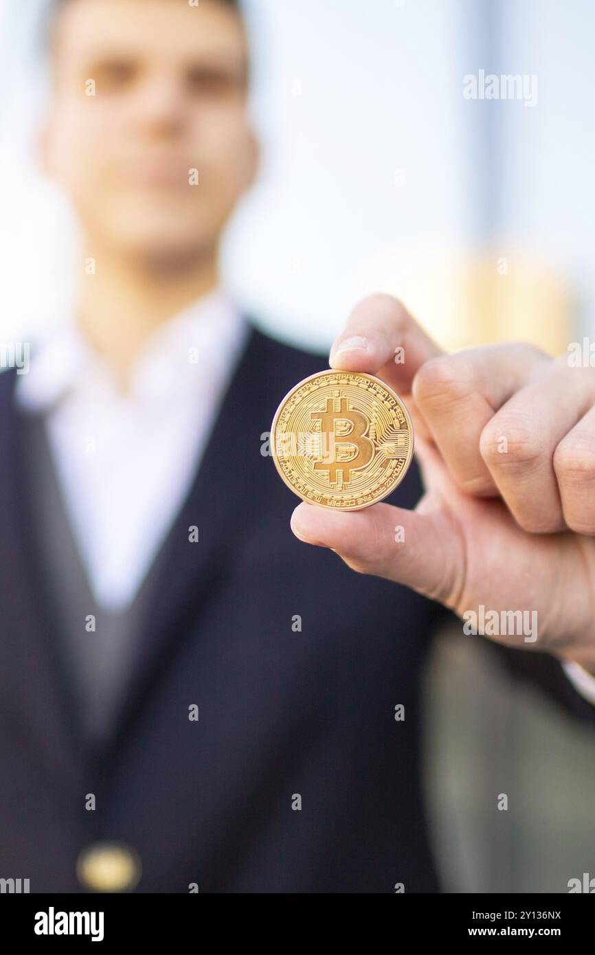 Bitcoin cryptocurrency coin in a young businessman hand. Disruptive ...