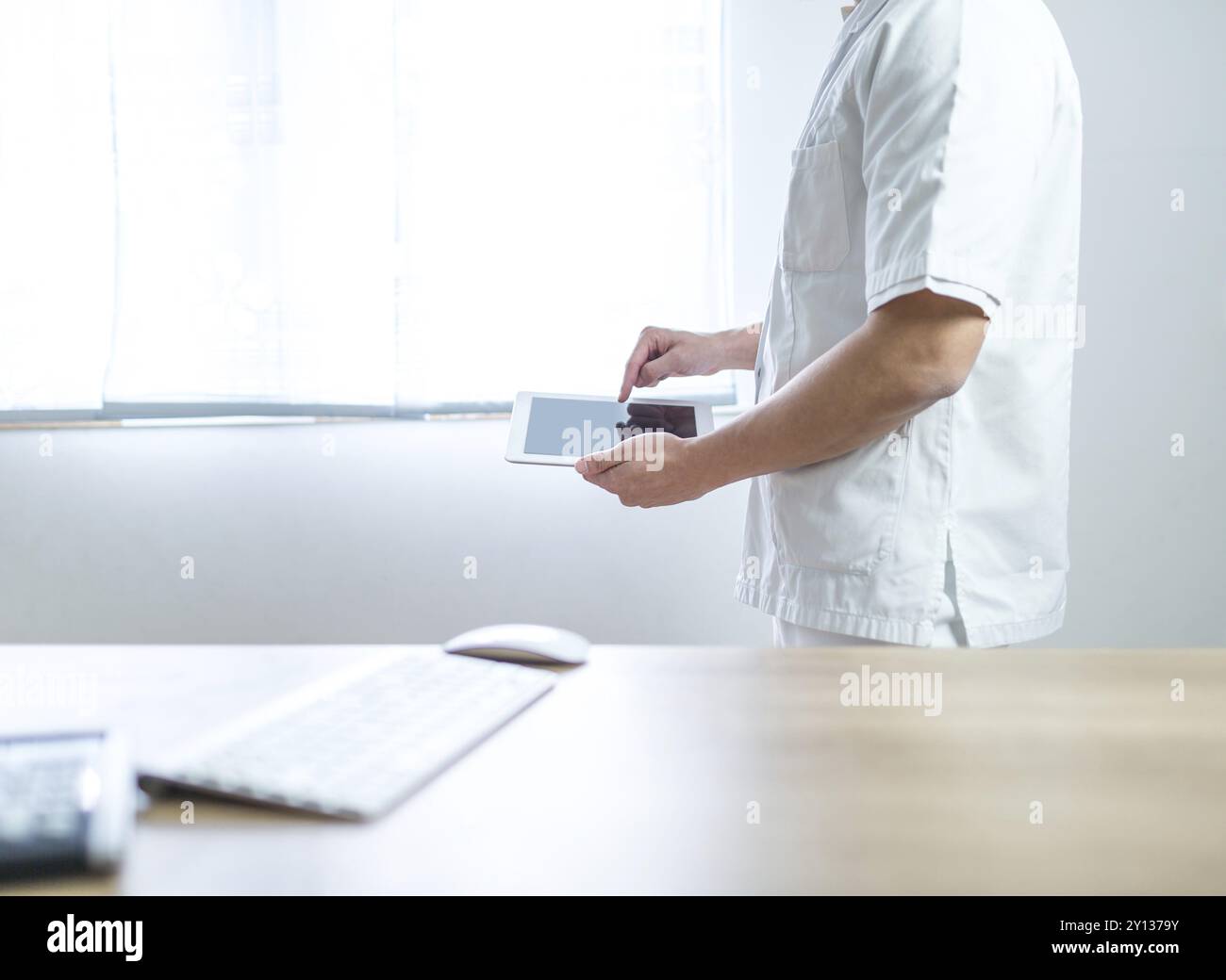 Doctor in the uniform using computer tablet next to his office desk in ...