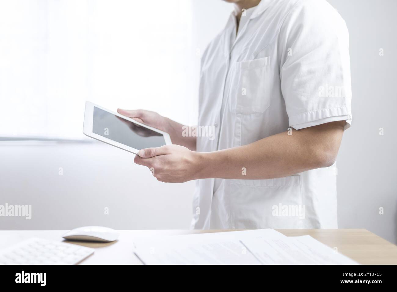 Doctor in the uniform using computer tablet next to his office desk in ...