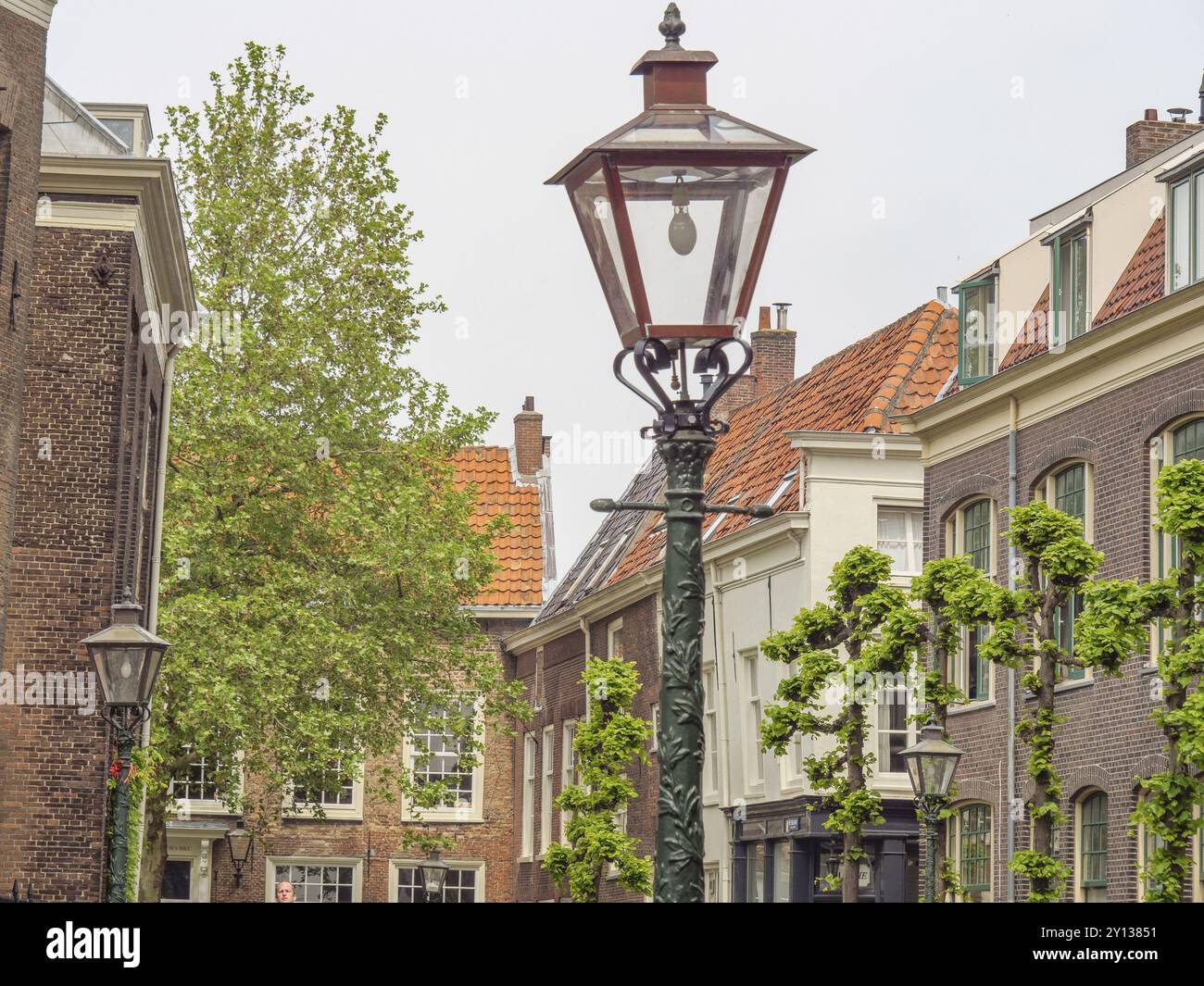 Urban scene with traditional brick houses, an old street lamp and green ...