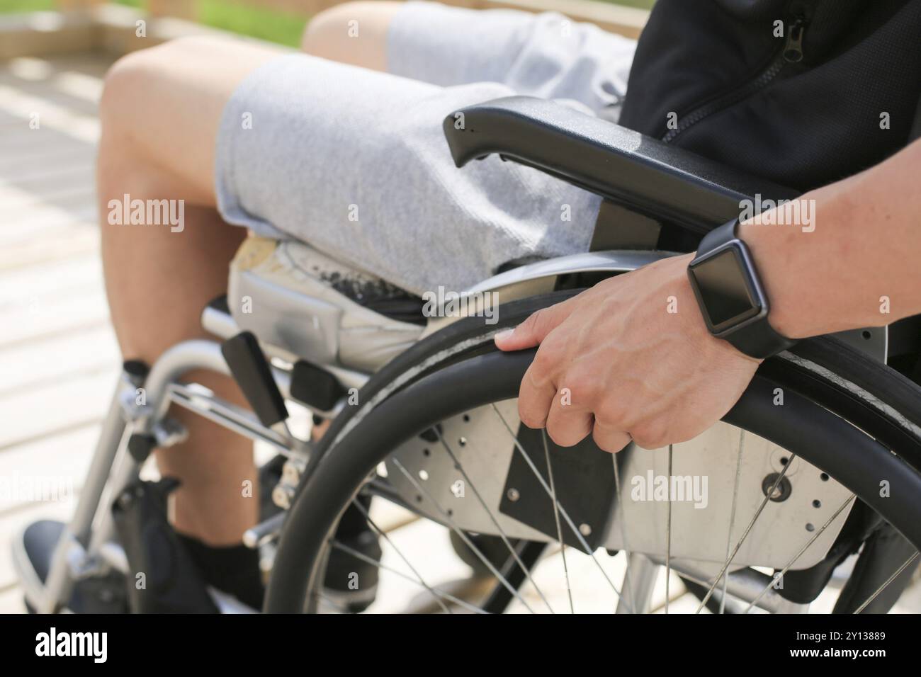Disabled young athletic man on a wheelchair holding and turning wheels ...