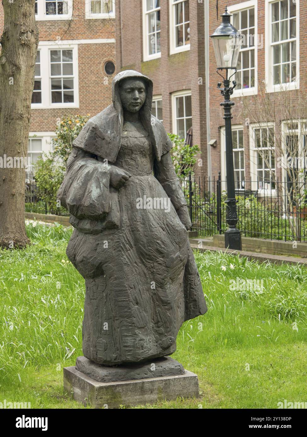Stone statue of a historically dressed woman in the garden in front of ...