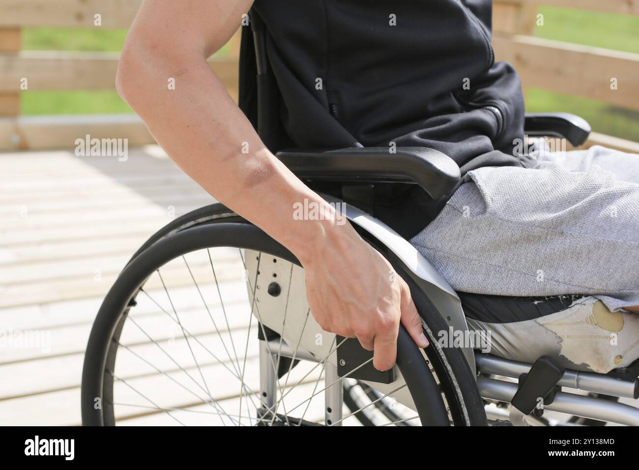 Disabled young athletic man on a wheelchair holding and turning wheels ...