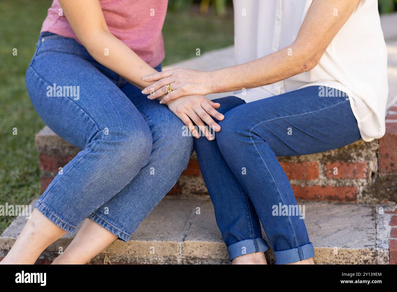 Holding hands, asian grandmother and gradndaughter sitting on steps ...