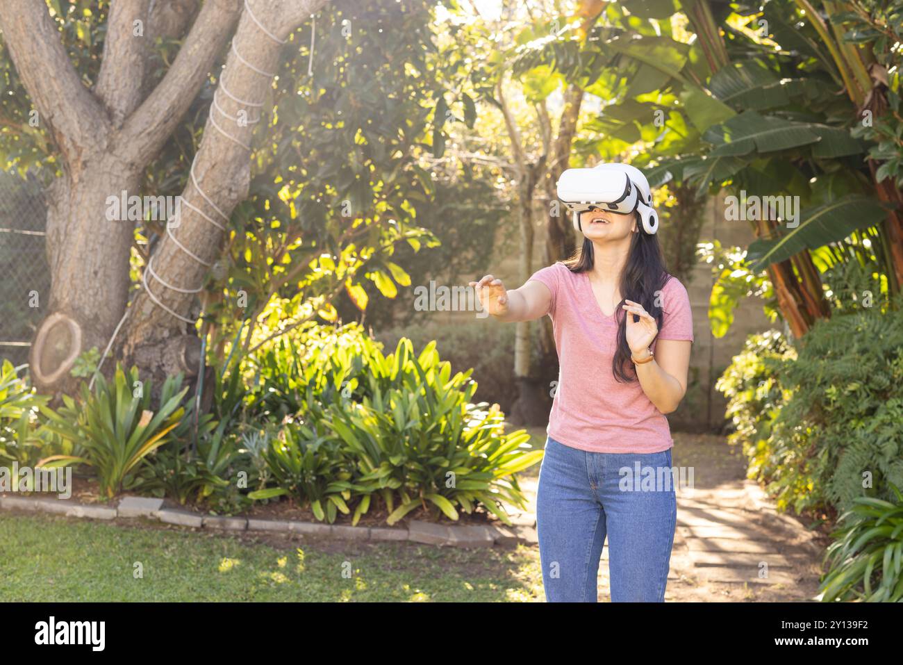 Using VR headset, asian woman exploring virtual reality in lush garden ...