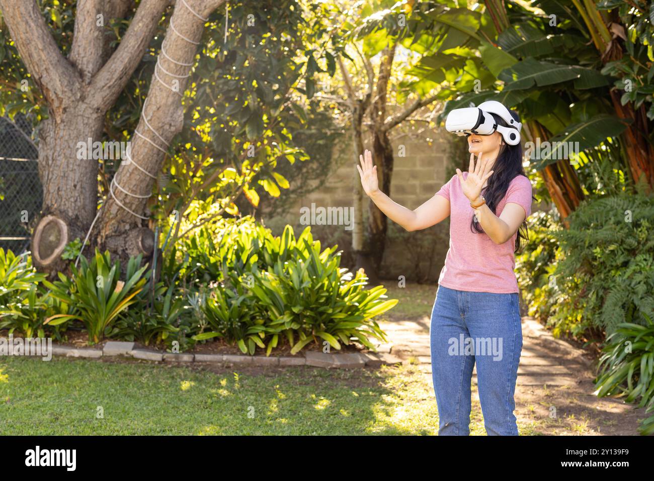 Using VR headset, asian woman exploring virtual reality in lush garden ...