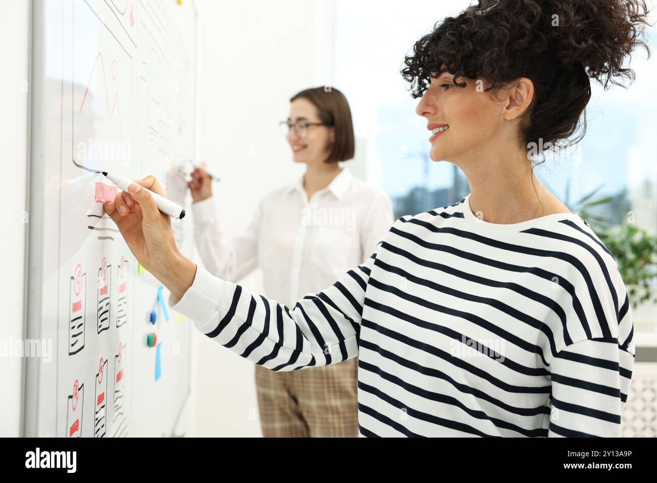 Developing UI design. Women drawing website wireframe on whiteboard ...
