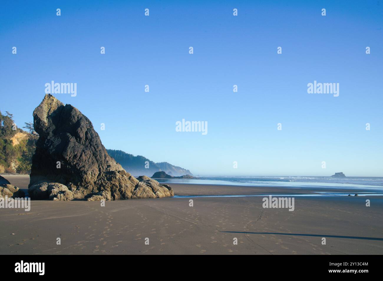 Large rock formation on the beach, with thin ribbons of tidal water ...