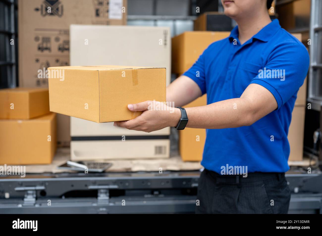 A cropped image of an Asian delivery guy in a blue uniform standing at ...