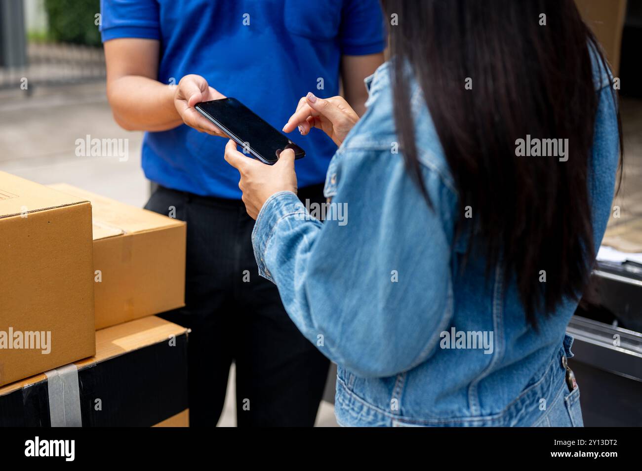 A close-up image of a female customer is signing on a smartphone before ...