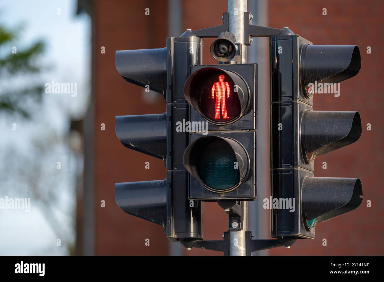 Red pedestrian signal illuminated, indicating stop, near a brick ...