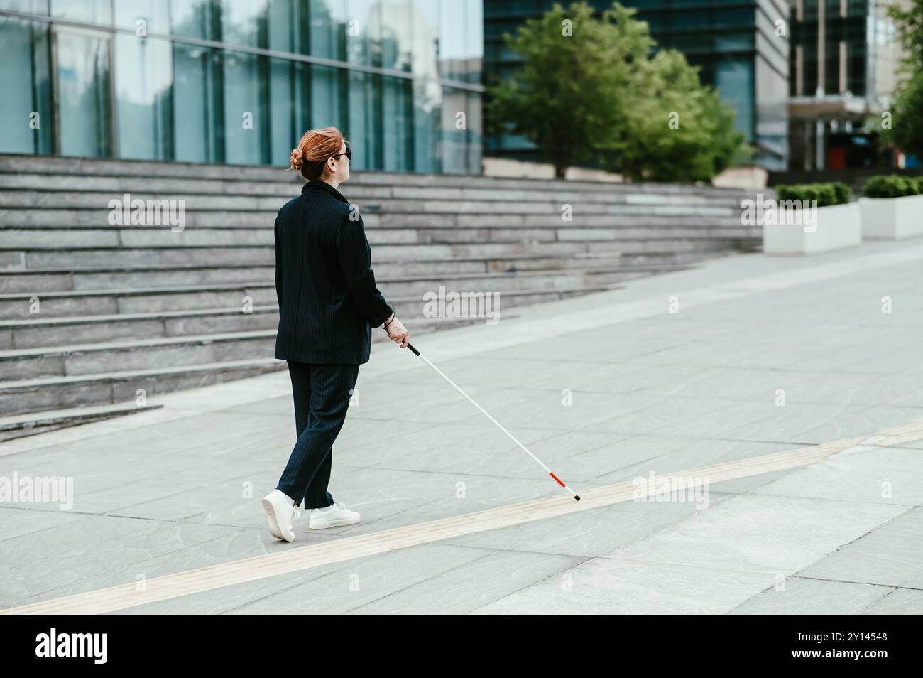 Blind businesswoman walking along tactile tiles with a cane Stock Photo ...