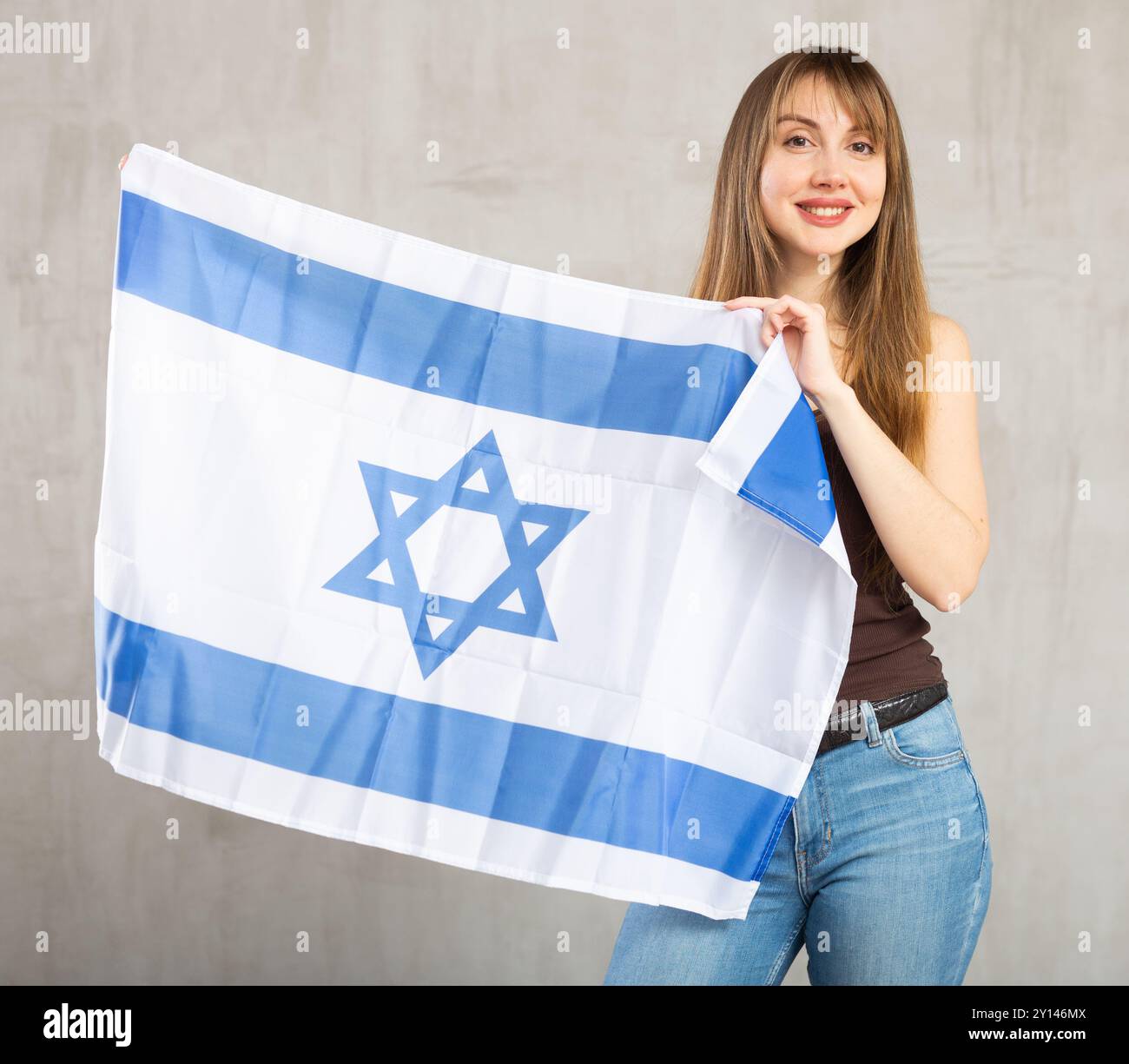 Joyful positive patriotic young woman holding state flag of Israel ...