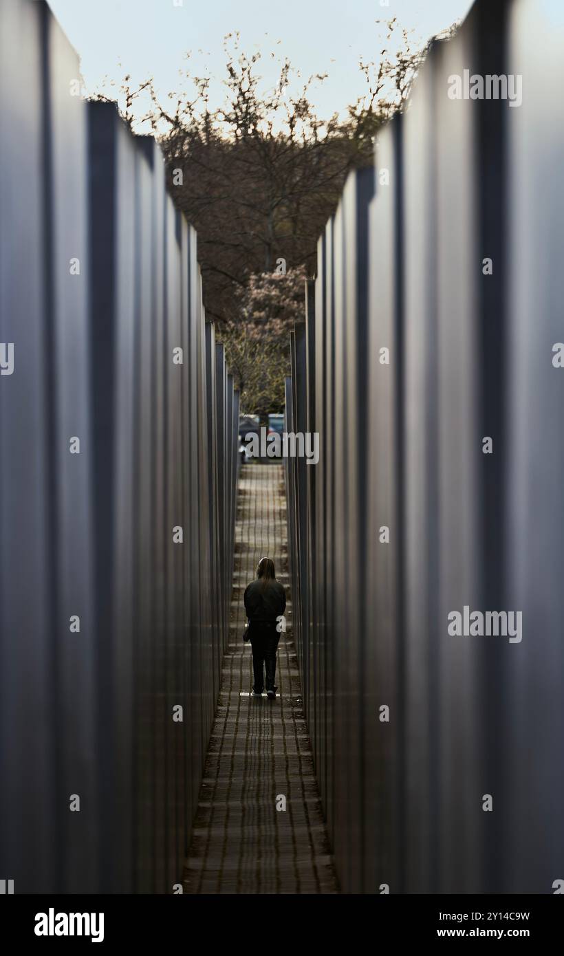 Lone person standing in the middle of long path between concrete ...