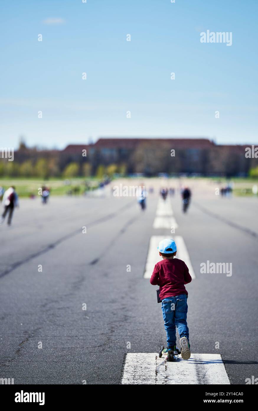 Ready steady go : child riding a scooter on a large airport runway. Kid ...