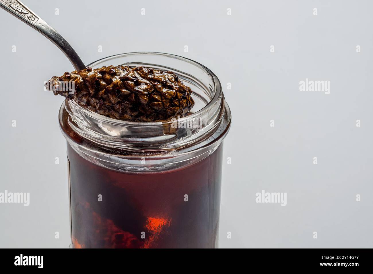 A jar of conifer syrup featuring a pine cone in honey, representing ...