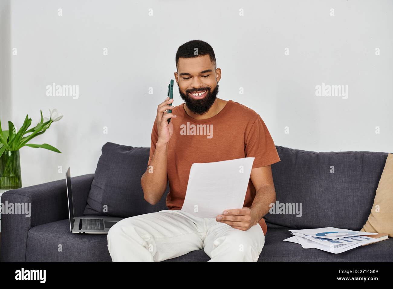 Happy man chatting on the phone while going through important documents ...