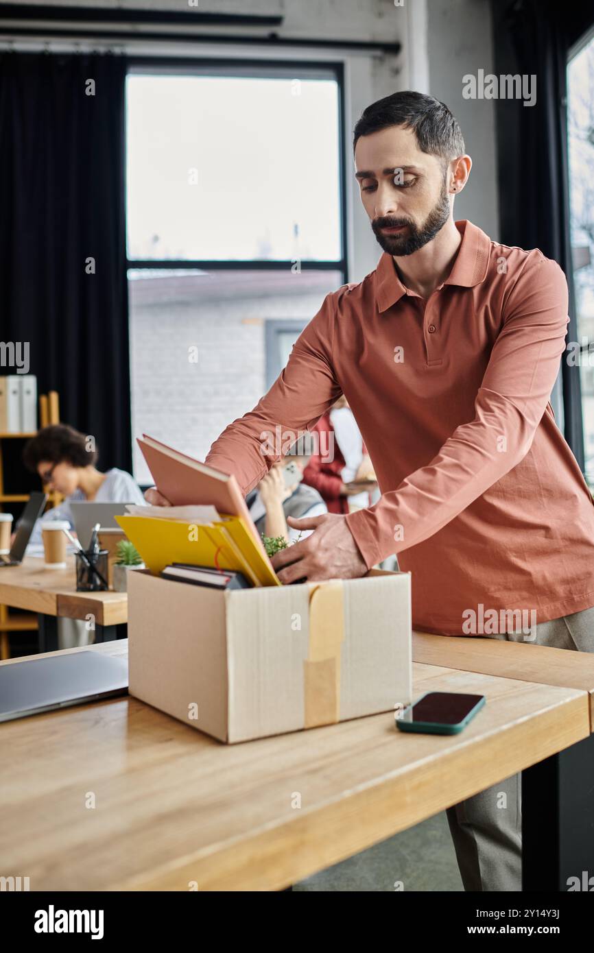 Fashionable man packing his items during lay off, colleagues on ...