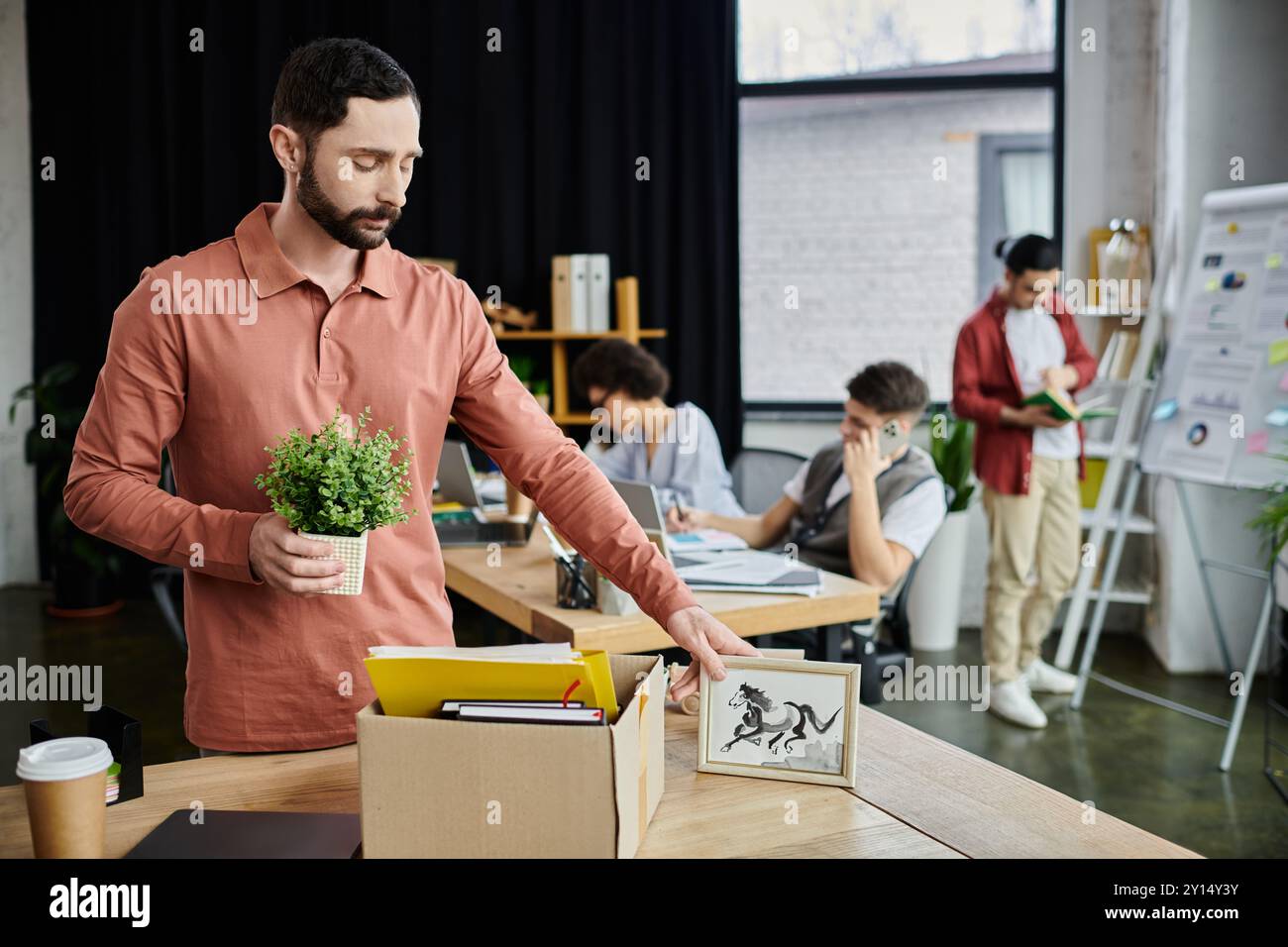 Exquisite man packing his items during lay off, colleagues on backdrop ...