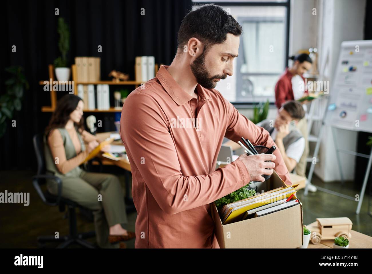 Dedicated man packing his belongings during lay off in modern office ...