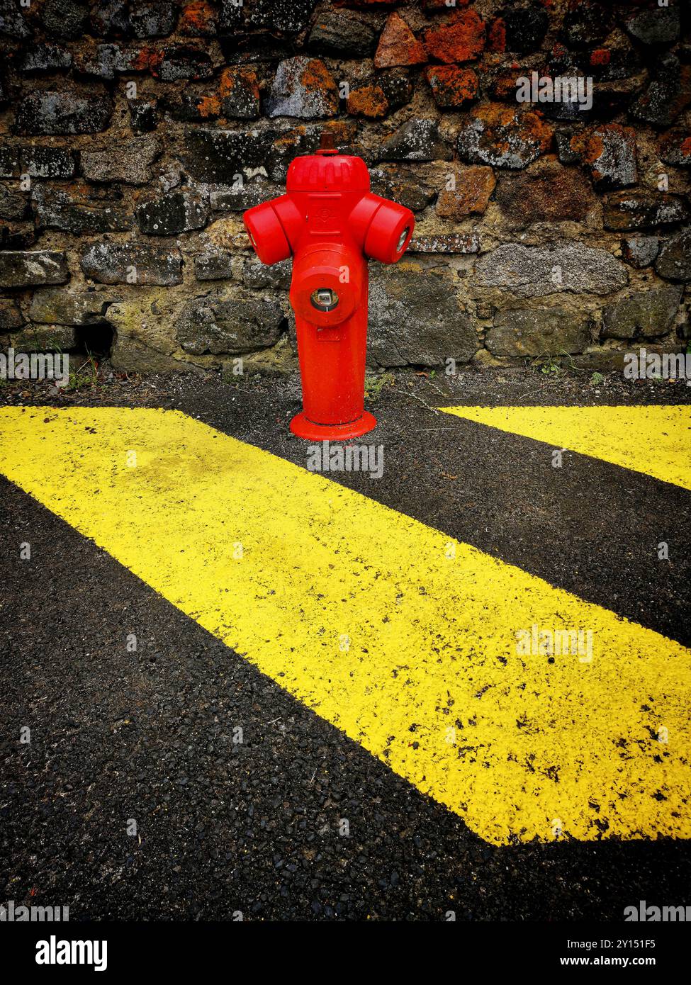 Bright red fire hydrant standing out against yellow lines on a textured ...
