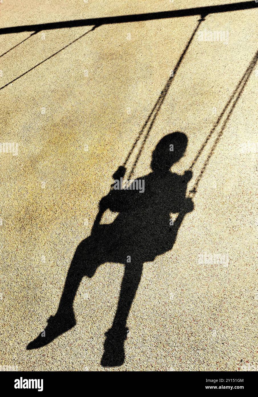 Silhouette of a child swinging on a sunny playground creating fine ...