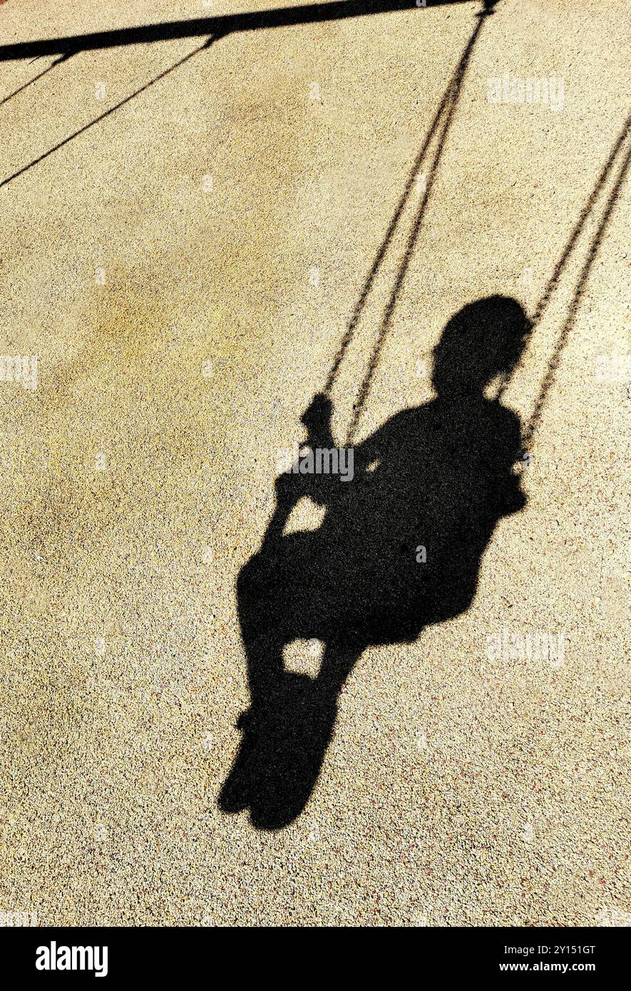 Silhouette of a child swinging on a sunny playground creating fine ...