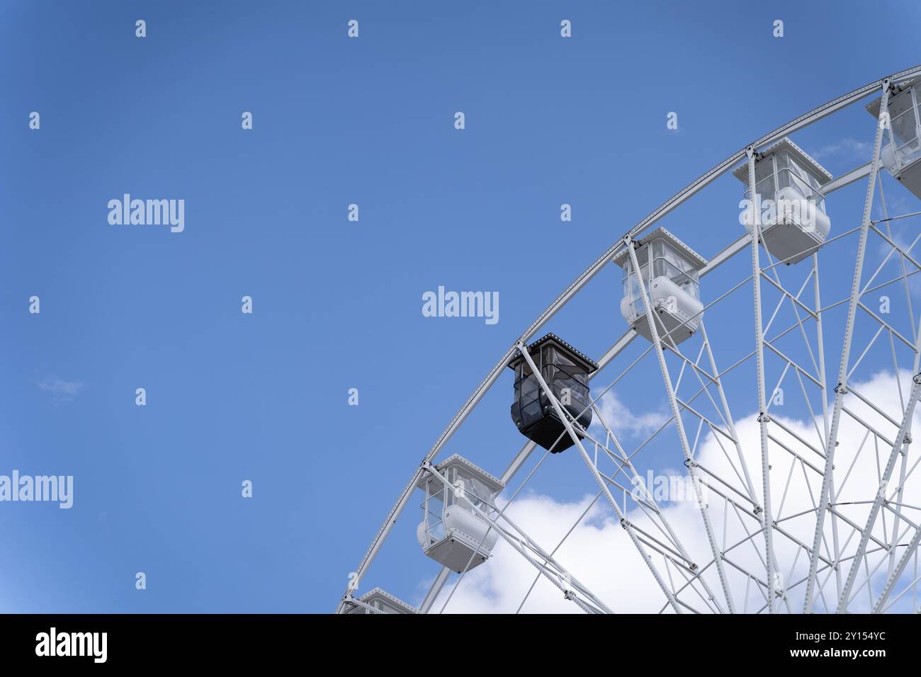 Partial view of a ferris wheel with white cabins and only one black ...