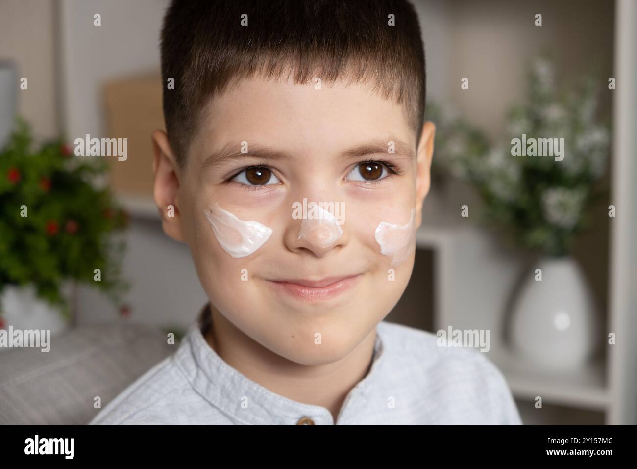 Cute seven-year-old boy with cosmetic cream on his face. Skin care and ...