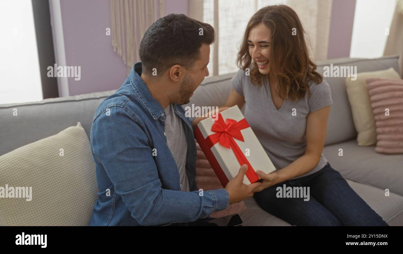 Couple sharing a gift in a cozy home setting with a woman smiling and a ...
