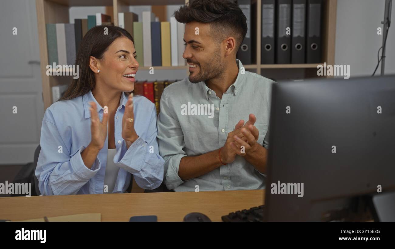 Man and woman clapping together in an office, both smiling and showing ...