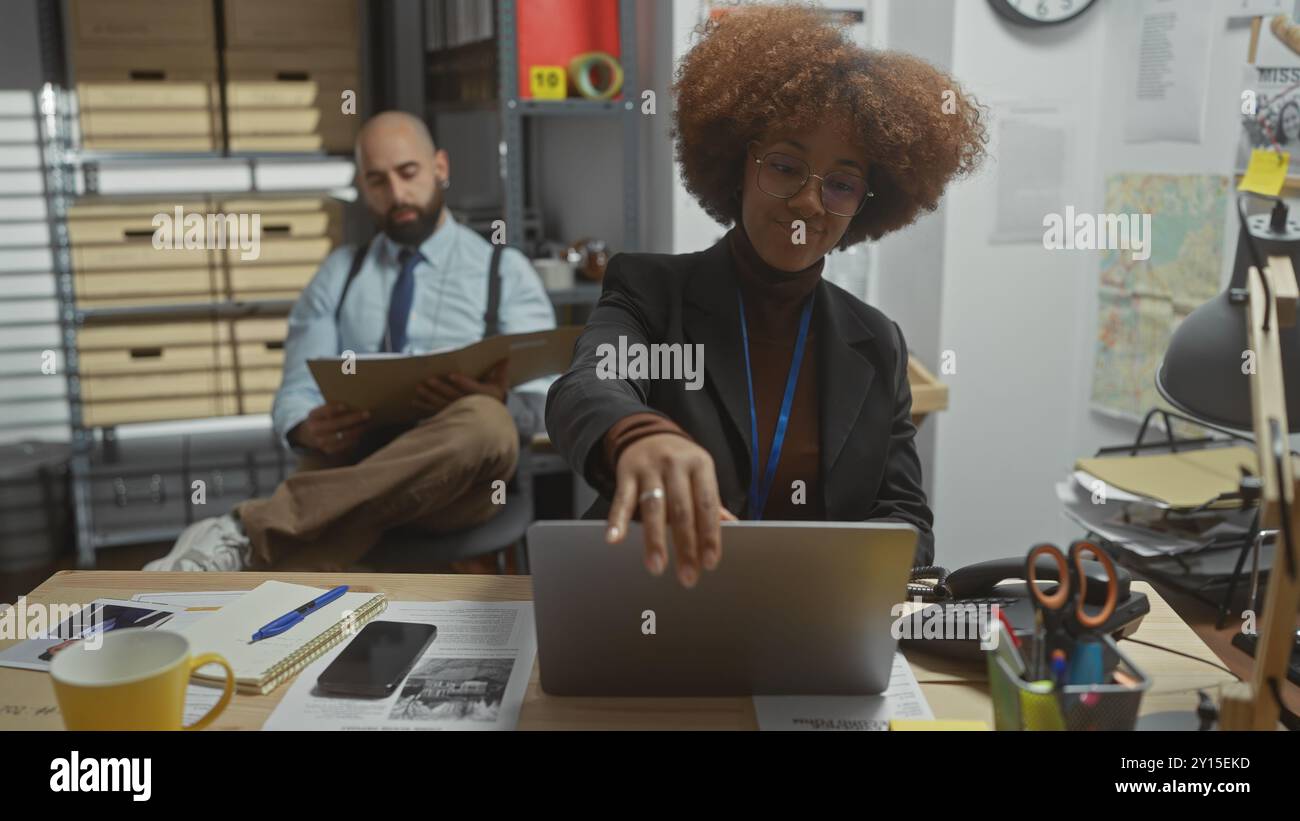 A woman and a man work as detectives in a cluttered police station ...
