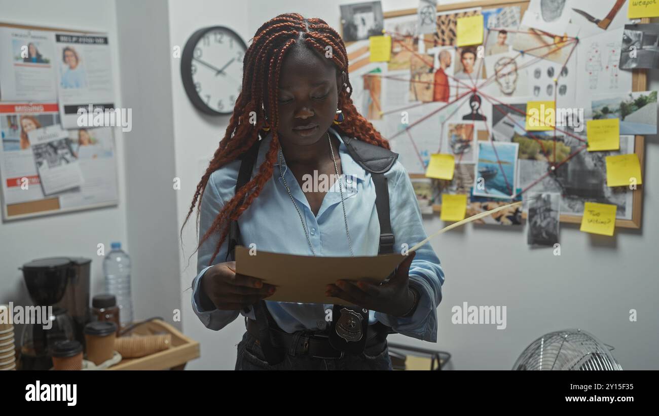 A focused african american woman detective examines a file in a police ...