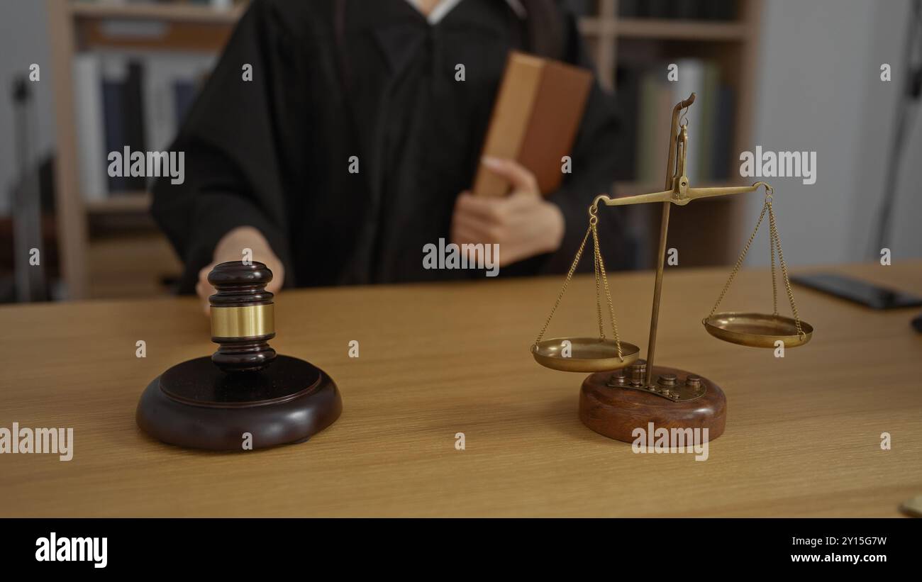 Judge holding book in courtroom with gavel and scales of justice on the ...